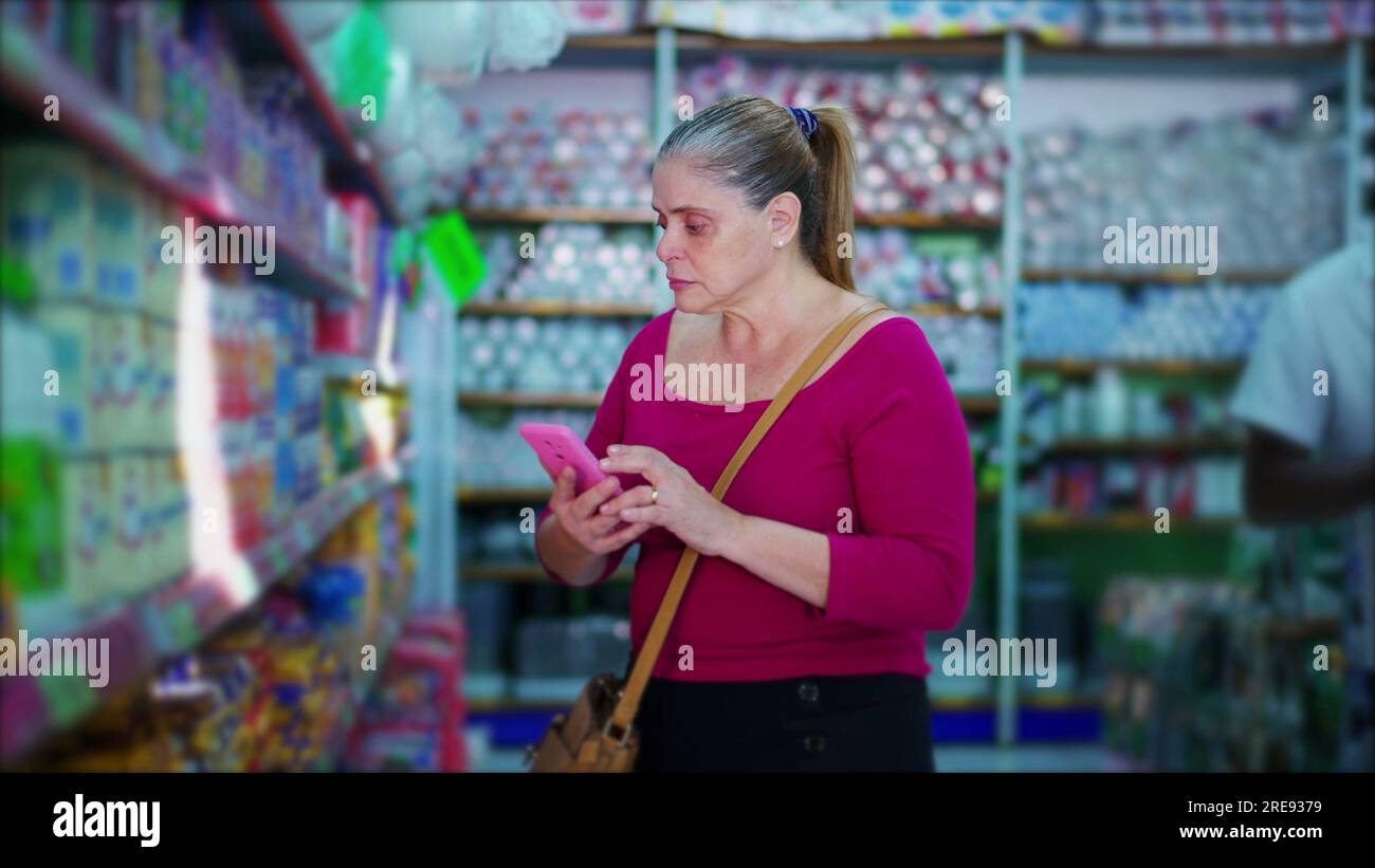 Woman Checking Product Details Online Using Mobile Phone At Grocery ...