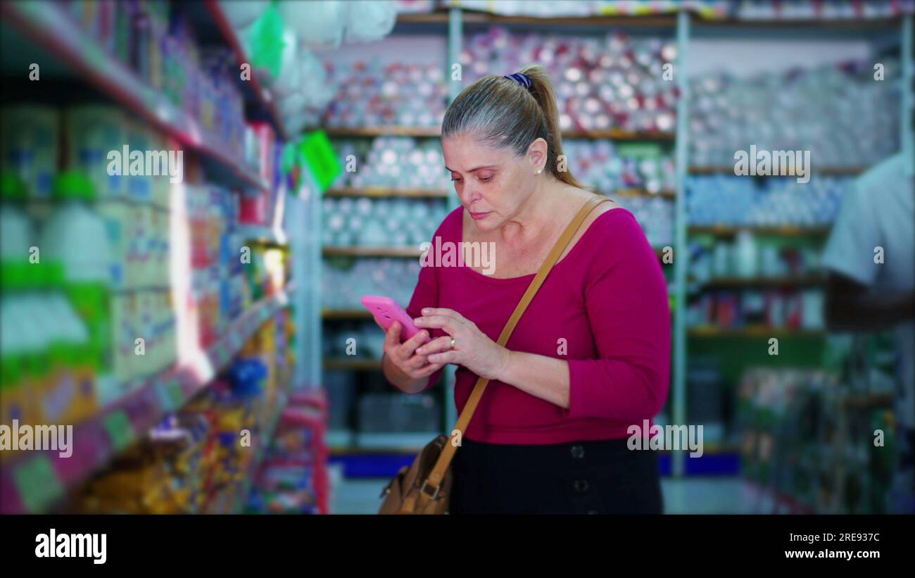 Woman Checking Product Details Online Using Mobile Phone At Grocery ...