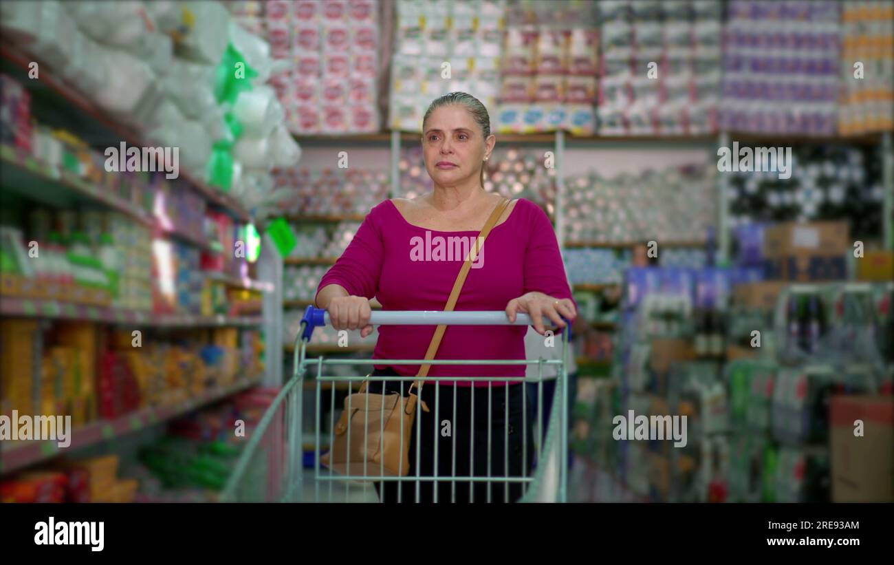 Female shopper walking through supermarket aisle browsing products on ...