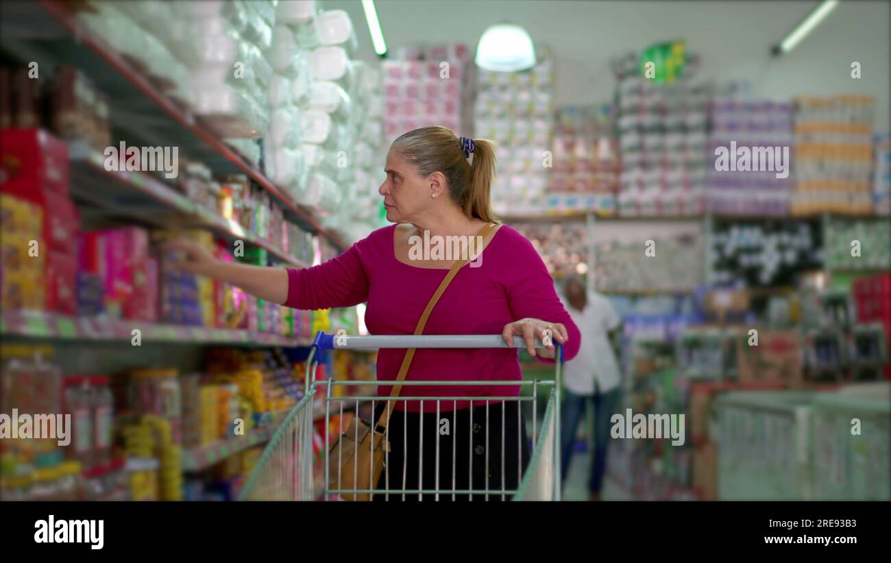 Female shopper walking through supermarket aisle browsing products on ...