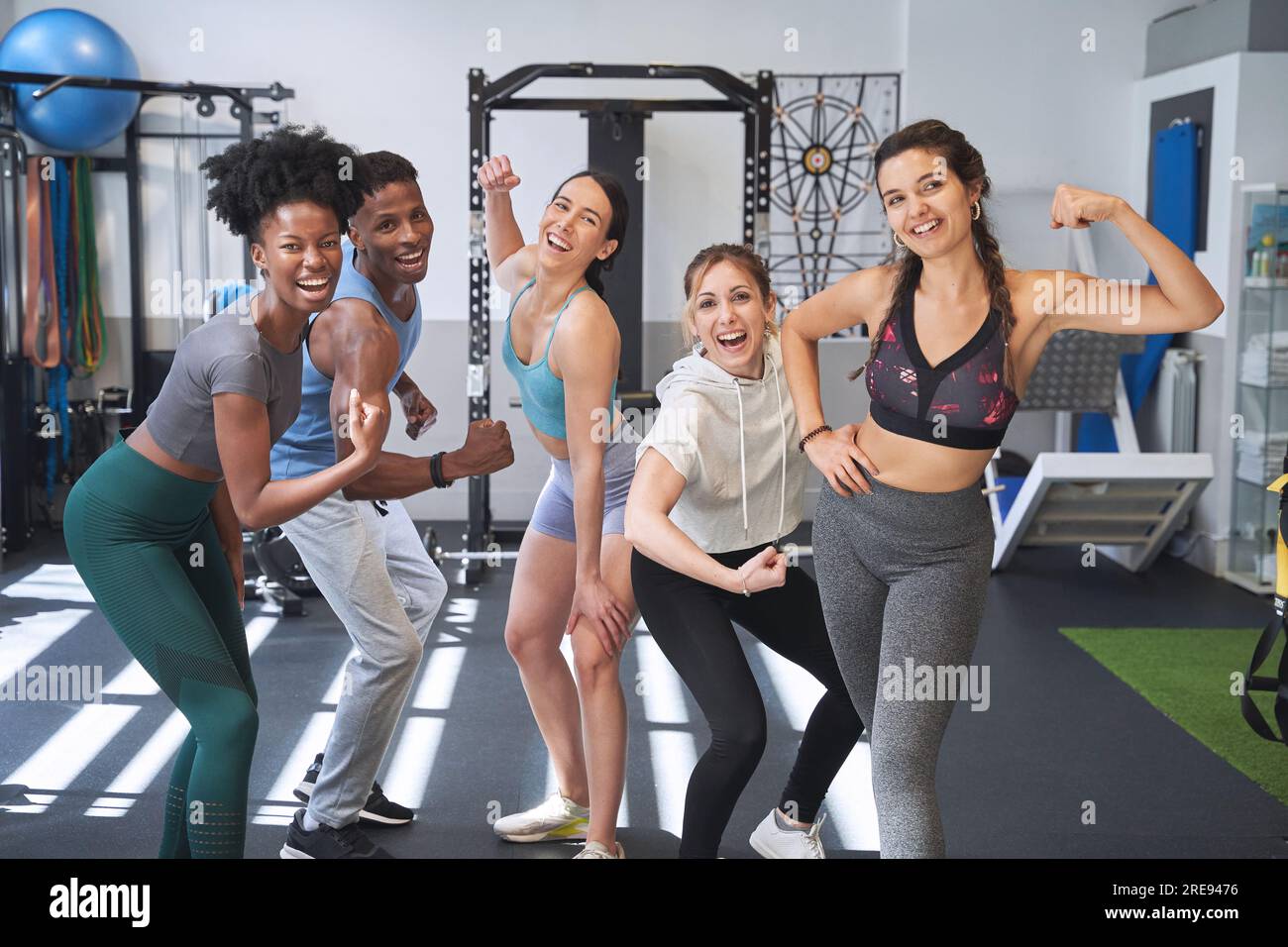 Group of sporty people showing arm muscles while posing in the gym ...