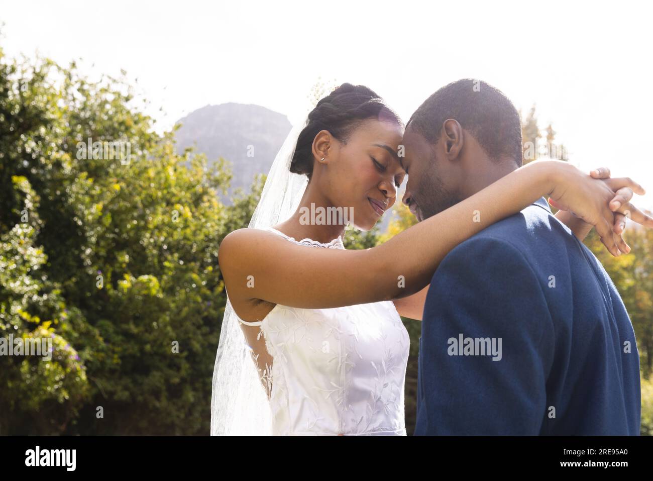 Happy african american bride and groom embracing at wedding in sunny ...