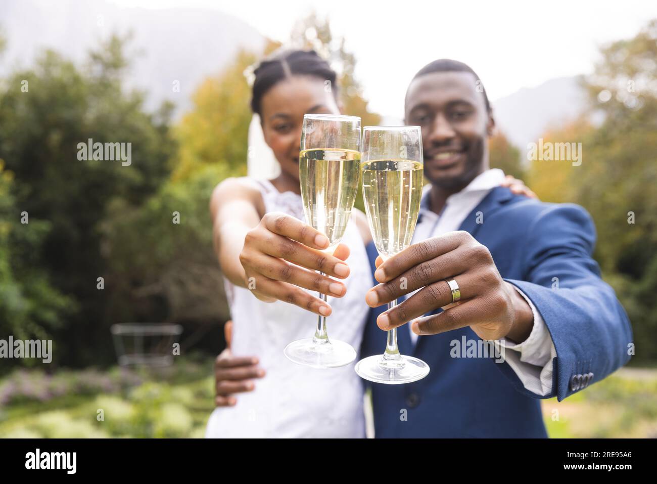 Happy african american bride and groom toasting with champagne at ...