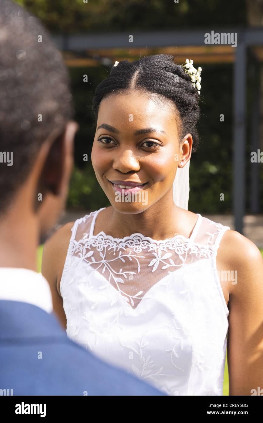 Smiling african american bride with groom at wedding ceremony in sunny ...