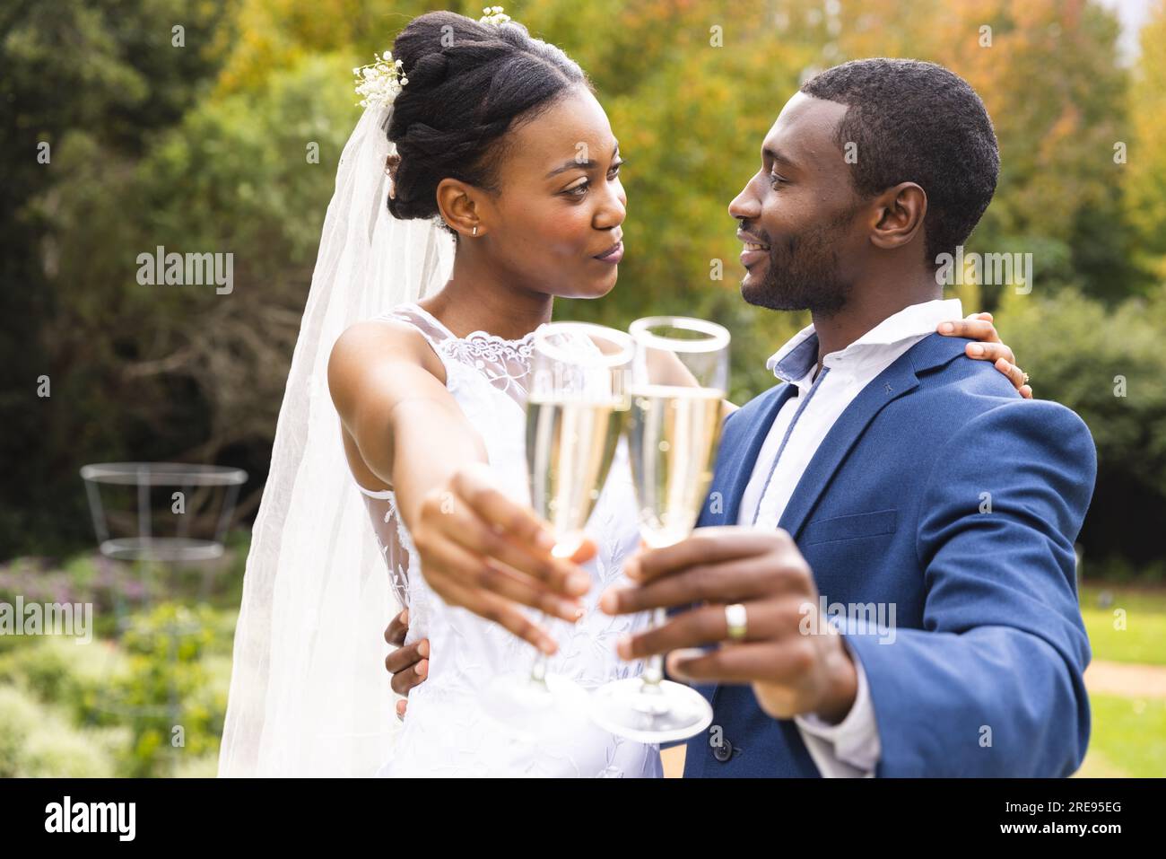 Happy african american bride and groom toasting with champagne smiling ...