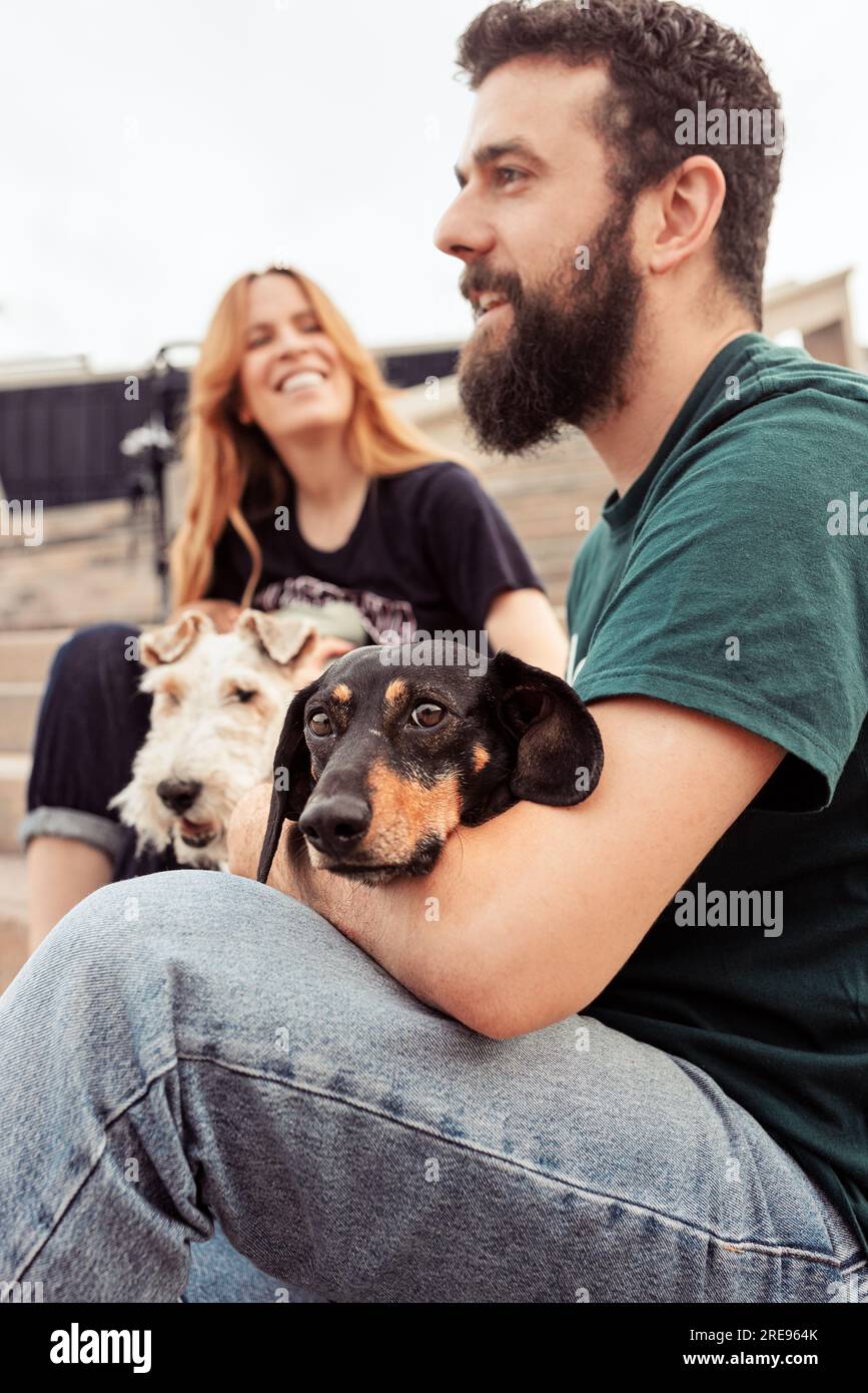Side view of smiling bearded man embracing Dachshund dog while sitting ...