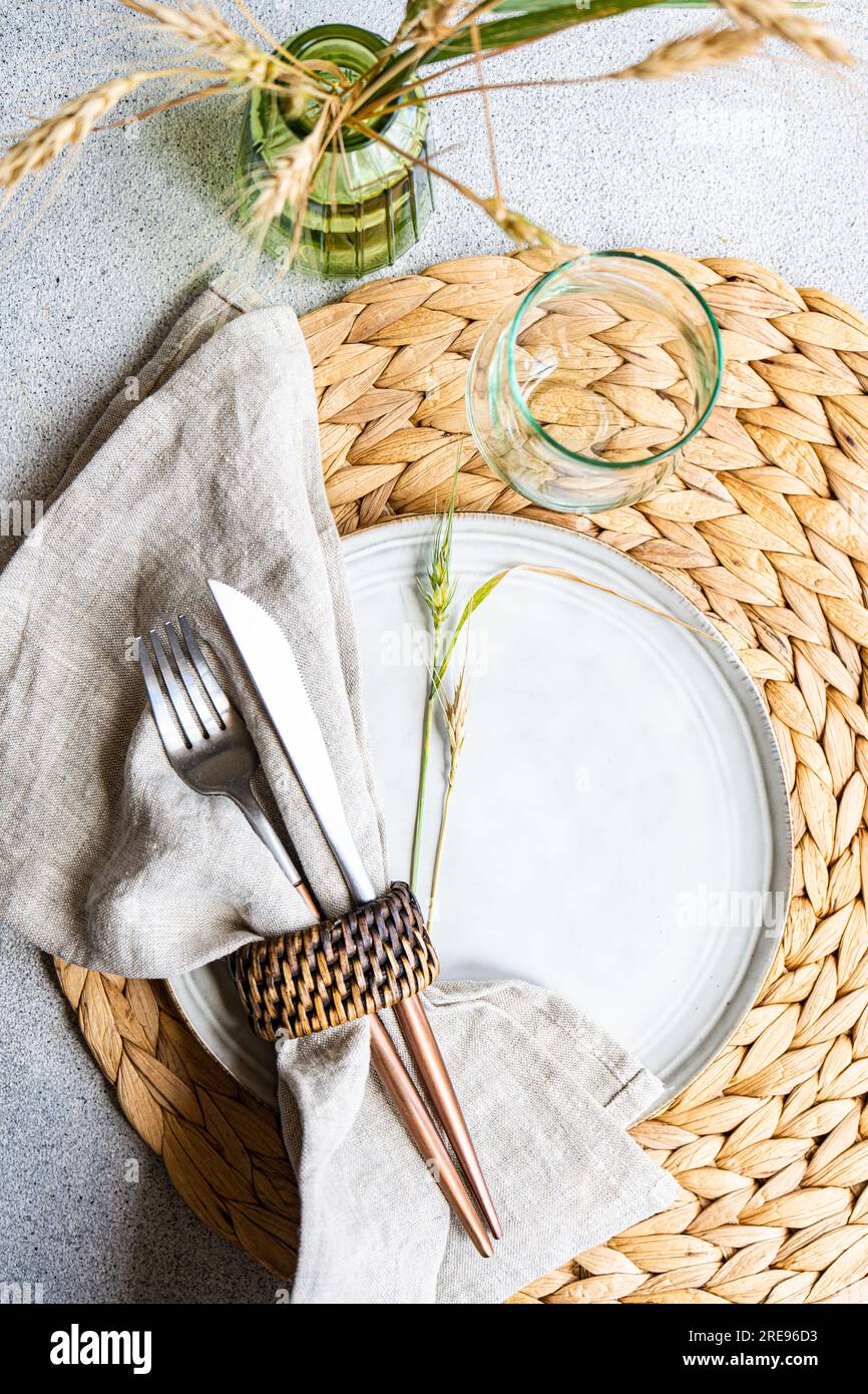 From above an elegant white ceramic plate with napkin-wrapped cutlery ...