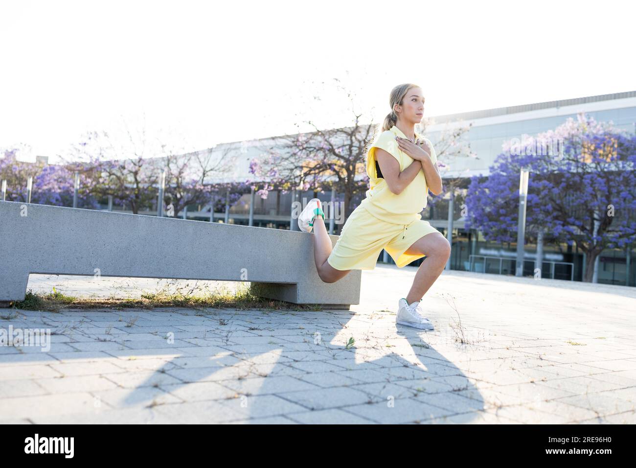 Full body view of young female athlete in sportswear squatting with ...