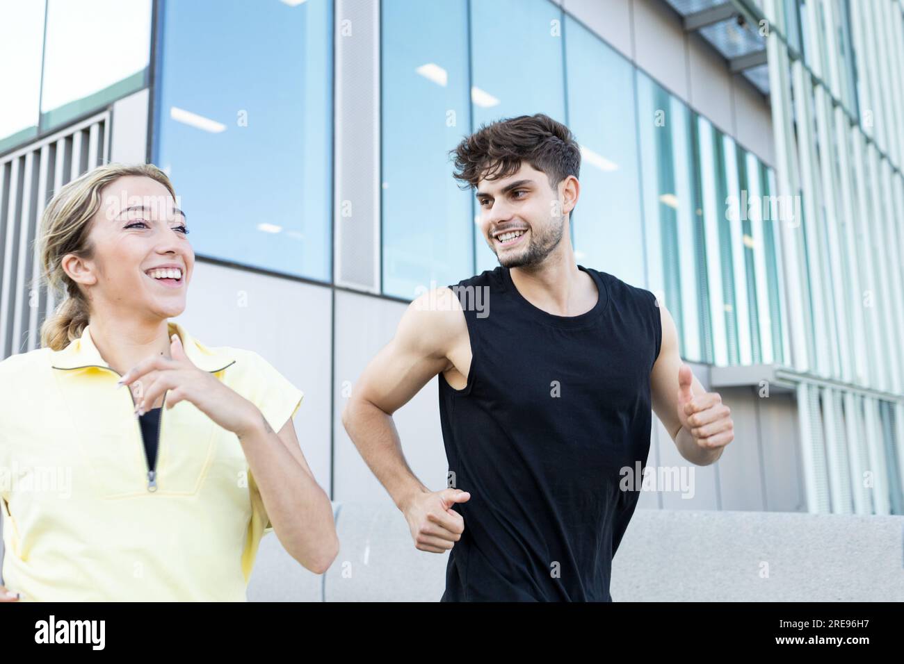 Focused happy athlete couple in sportswear while jogging on pavement ...