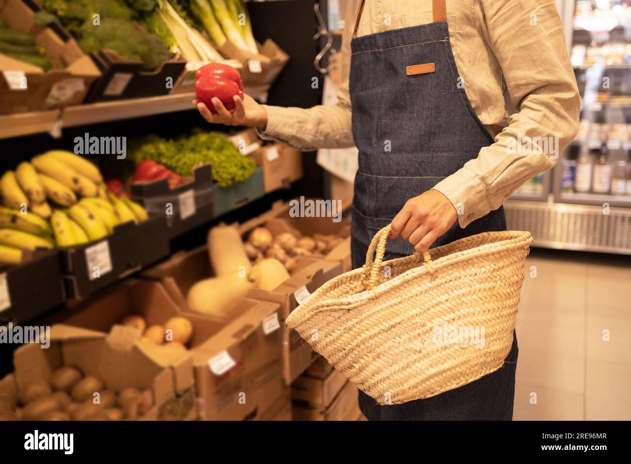 Cropped unrecognizable male seller in apron choosing fresh ripe bell ...