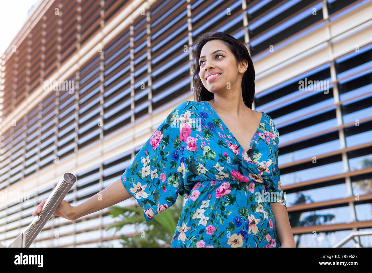 Low angle of smiling young Indian female with long dark hair looking ...