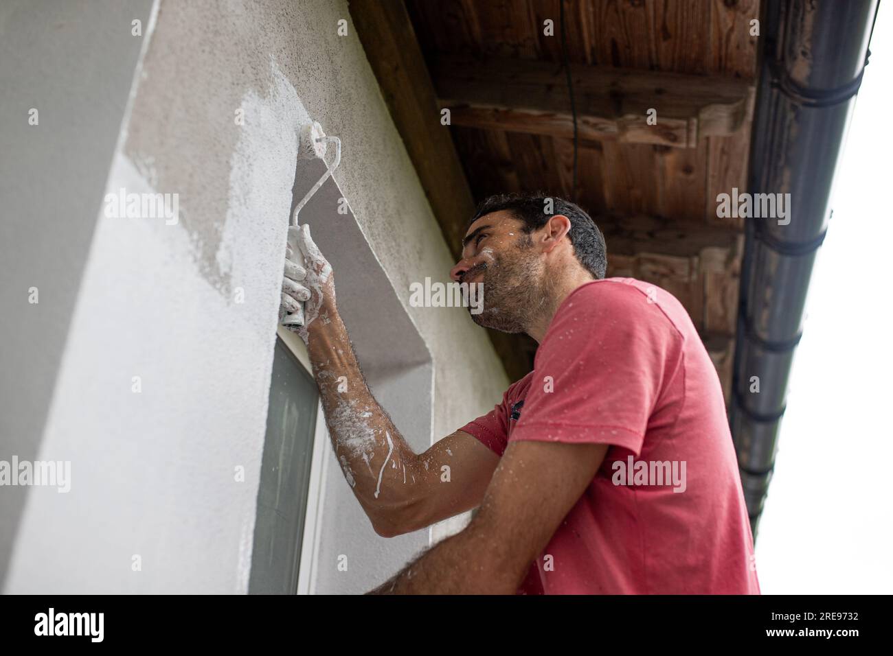 Low angle side view of bearded adult male painter in casual clothes ...