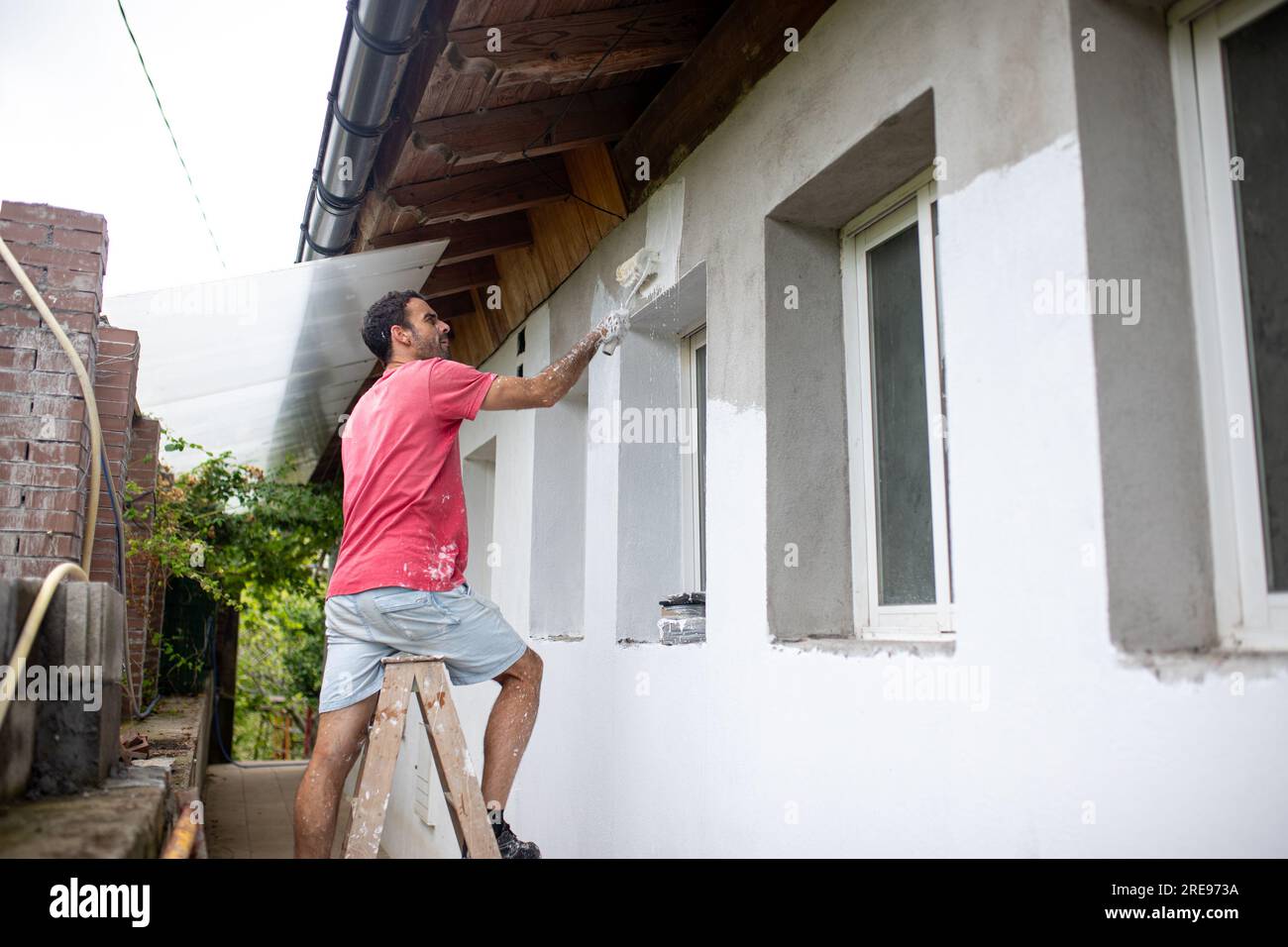 Low angle side view of bearded adult male painter in casual clothes ...