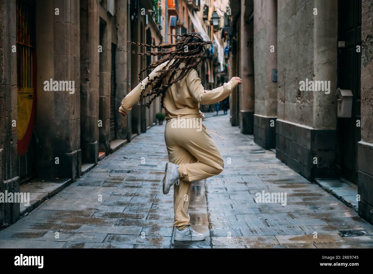Full body back view of anonymous female with braids in beige outfit and ...