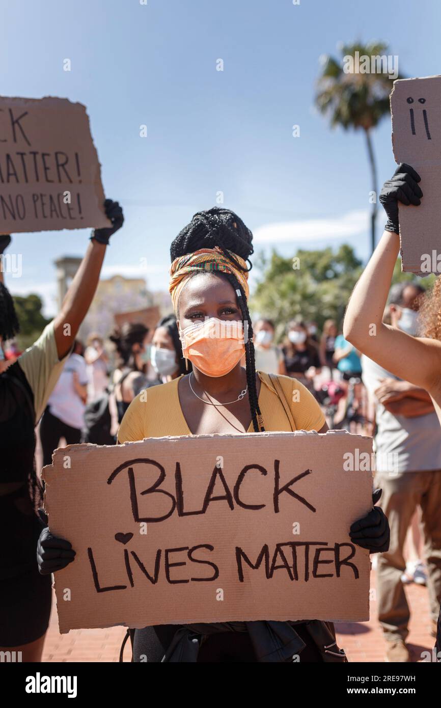 Serious ethnic female with afro hairstyle holding cardboard poster with ...