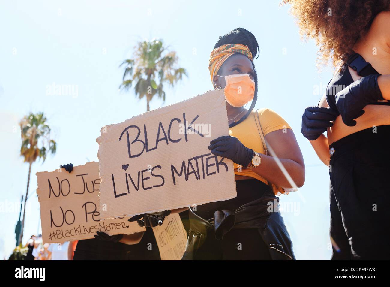Serious ethnic female with afro hairstyle holding cardboard poster with ...