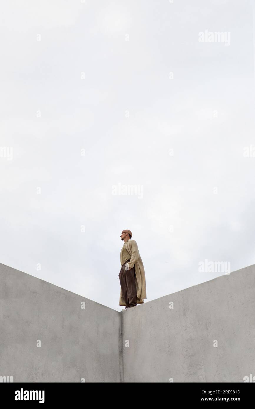 Low angle side view of lonely male standing with hands in pockets on ...