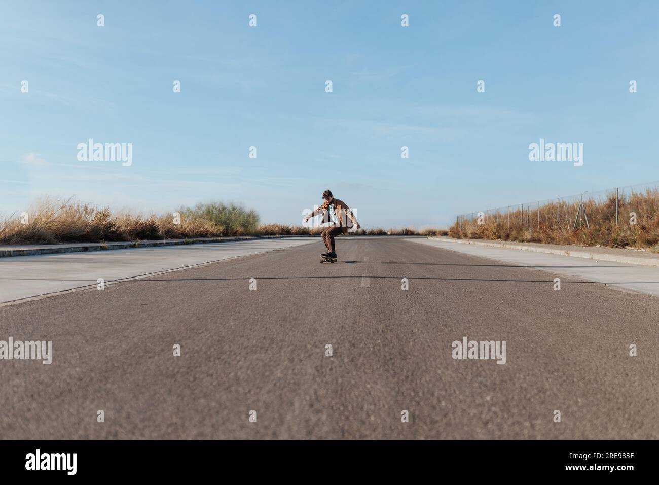 Full body young bearded male skater in stylish wear riding skateboard ...