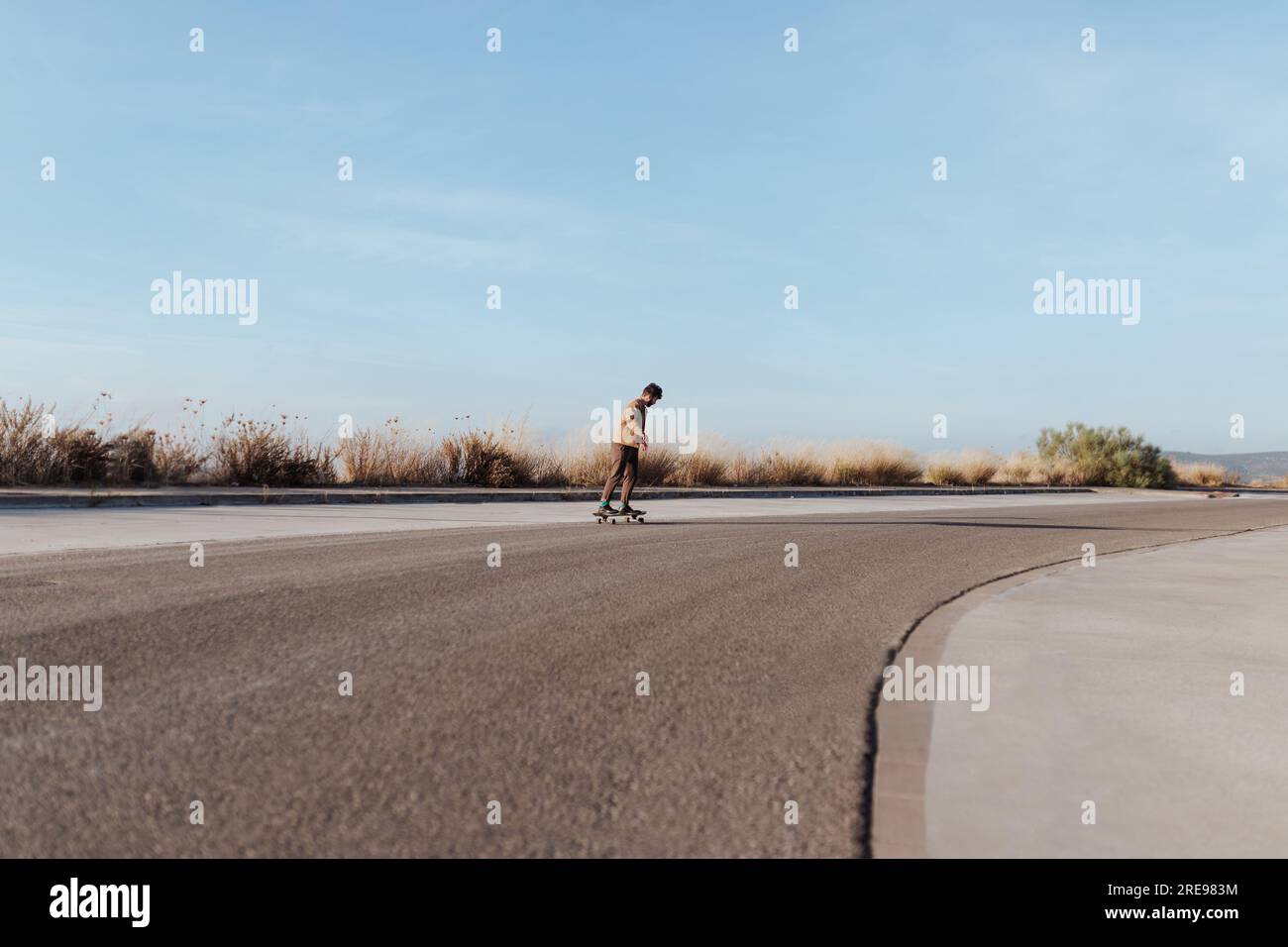 Full body young bearded male skater in stylish wear riding skateboard ...