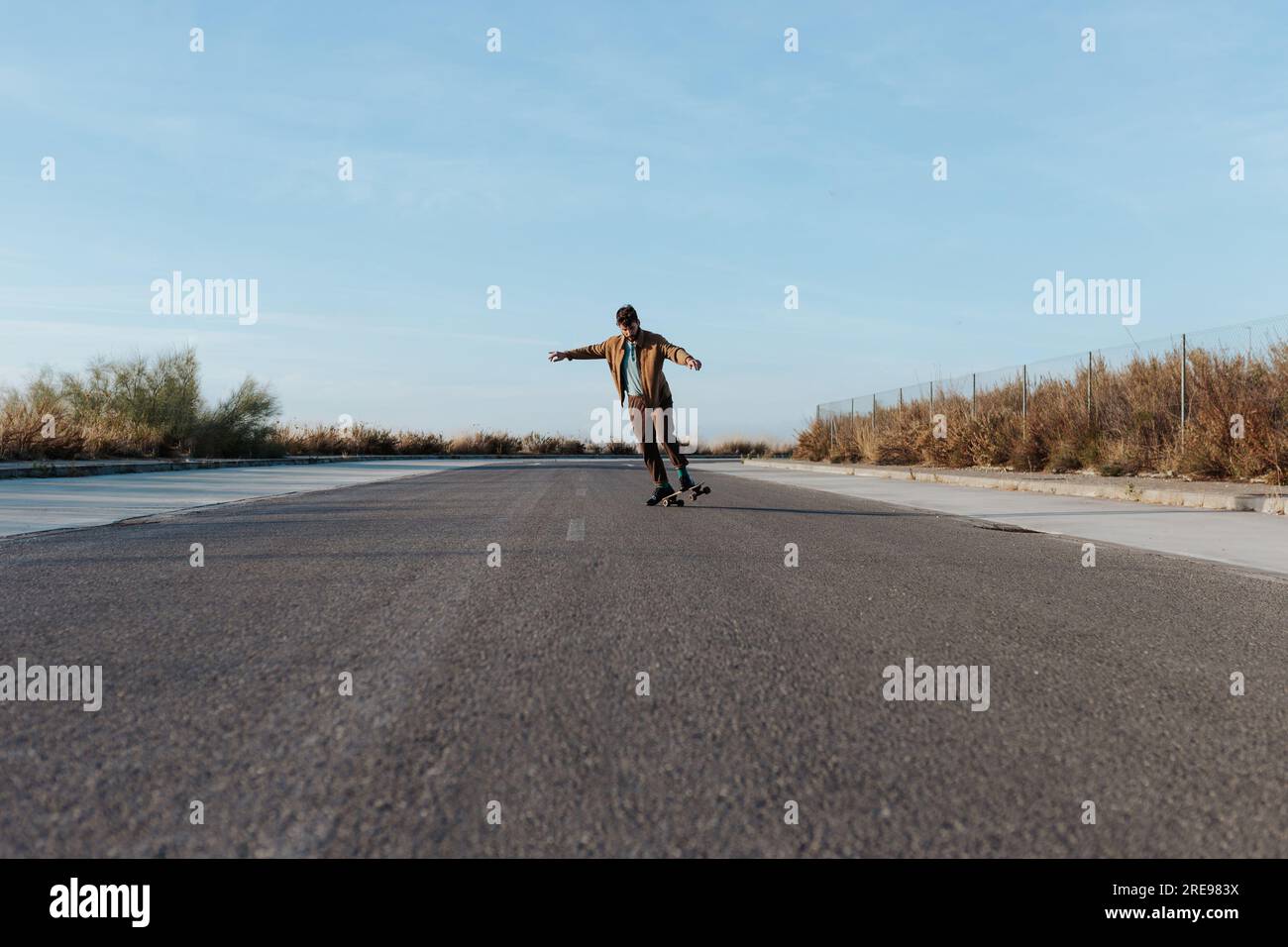 Full body young bearded male skater in stylish wear riding skateboard ...