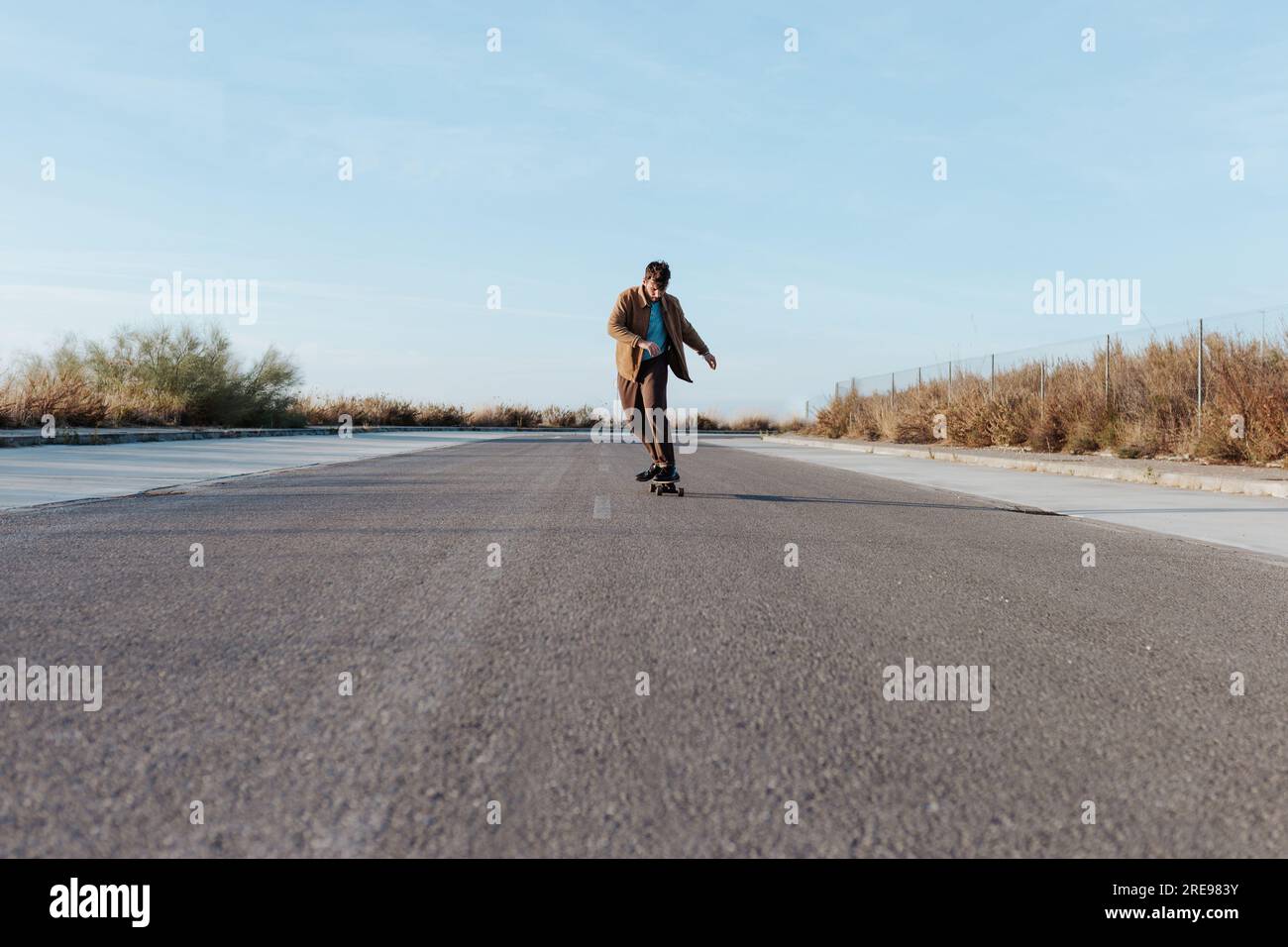 Full body young bearded male skater in stylish wear riding skateboard ...
