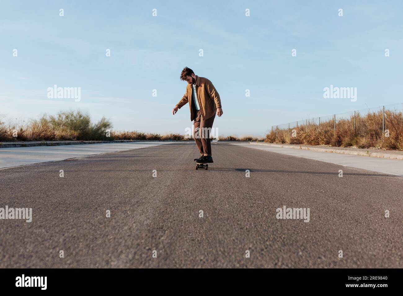 Full body young bearded male skater in stylish wear riding skateboard ...
