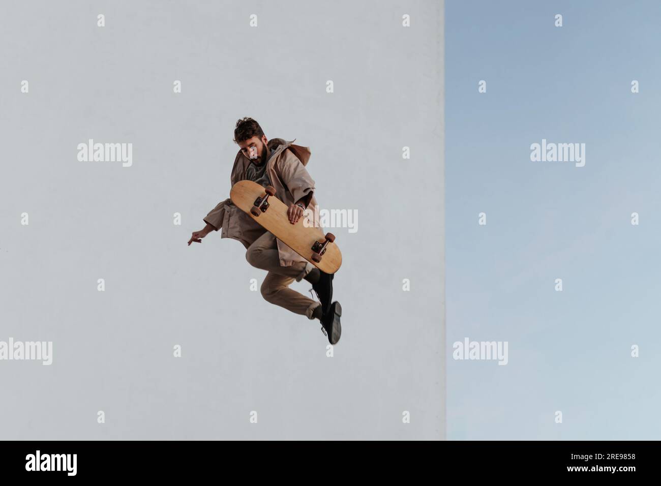 Full body young bearded active male skater in casual outfit jumping ...