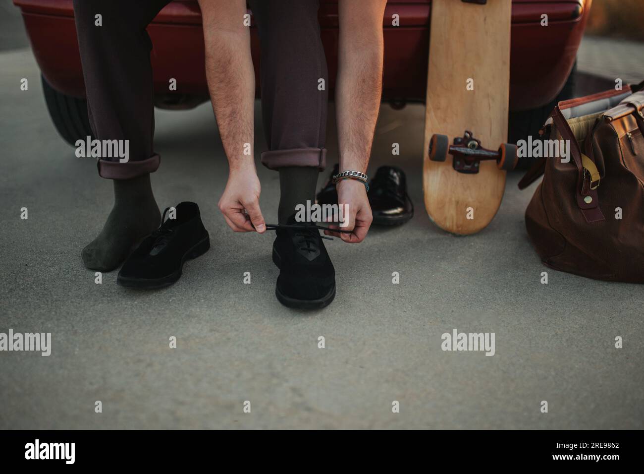 From above of crop unrecognizable male skater sitting on car trunk near ...