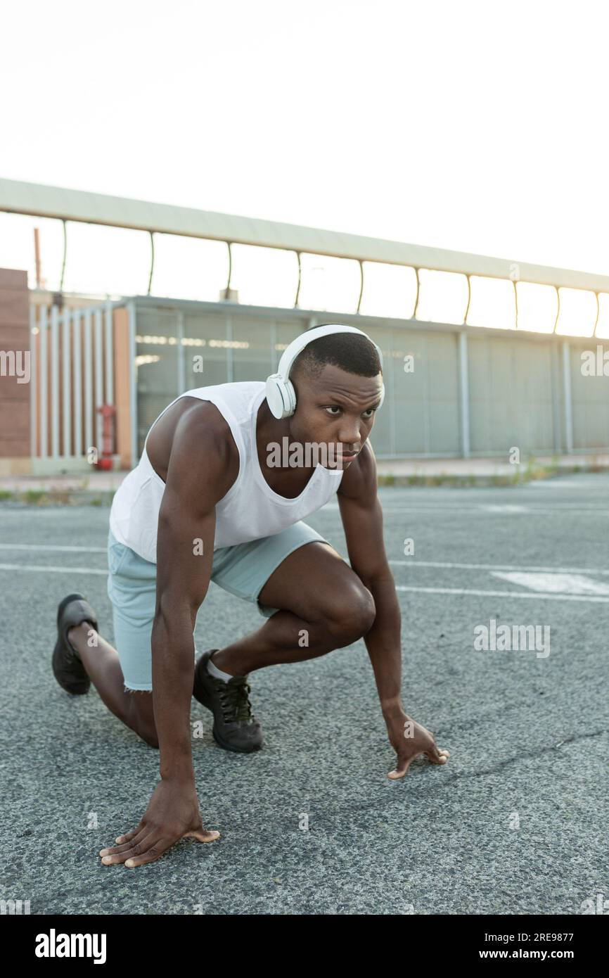 Full body side view of concentrated African American sportsman ready to ...
