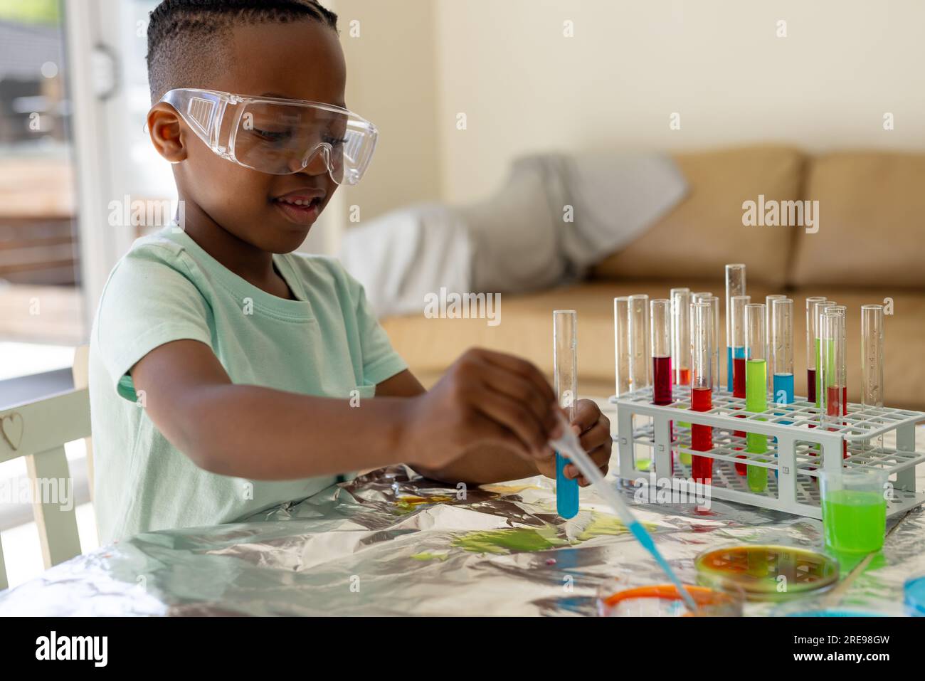 Happy african american boy doing chemistry experiments at home in sunny ...