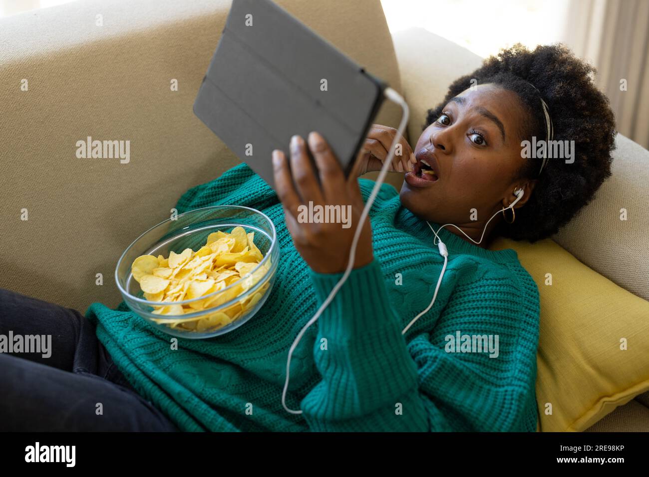 Plus Size African American Woman With Earphones Lying On Sofa Watching