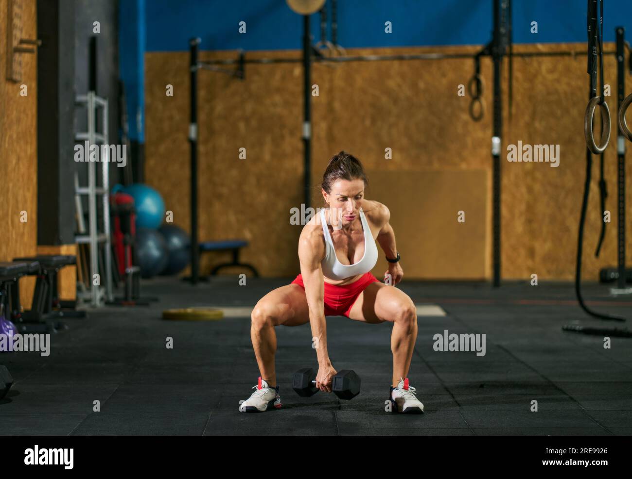 Full body of strong female athlete in activewear doing squats and ...