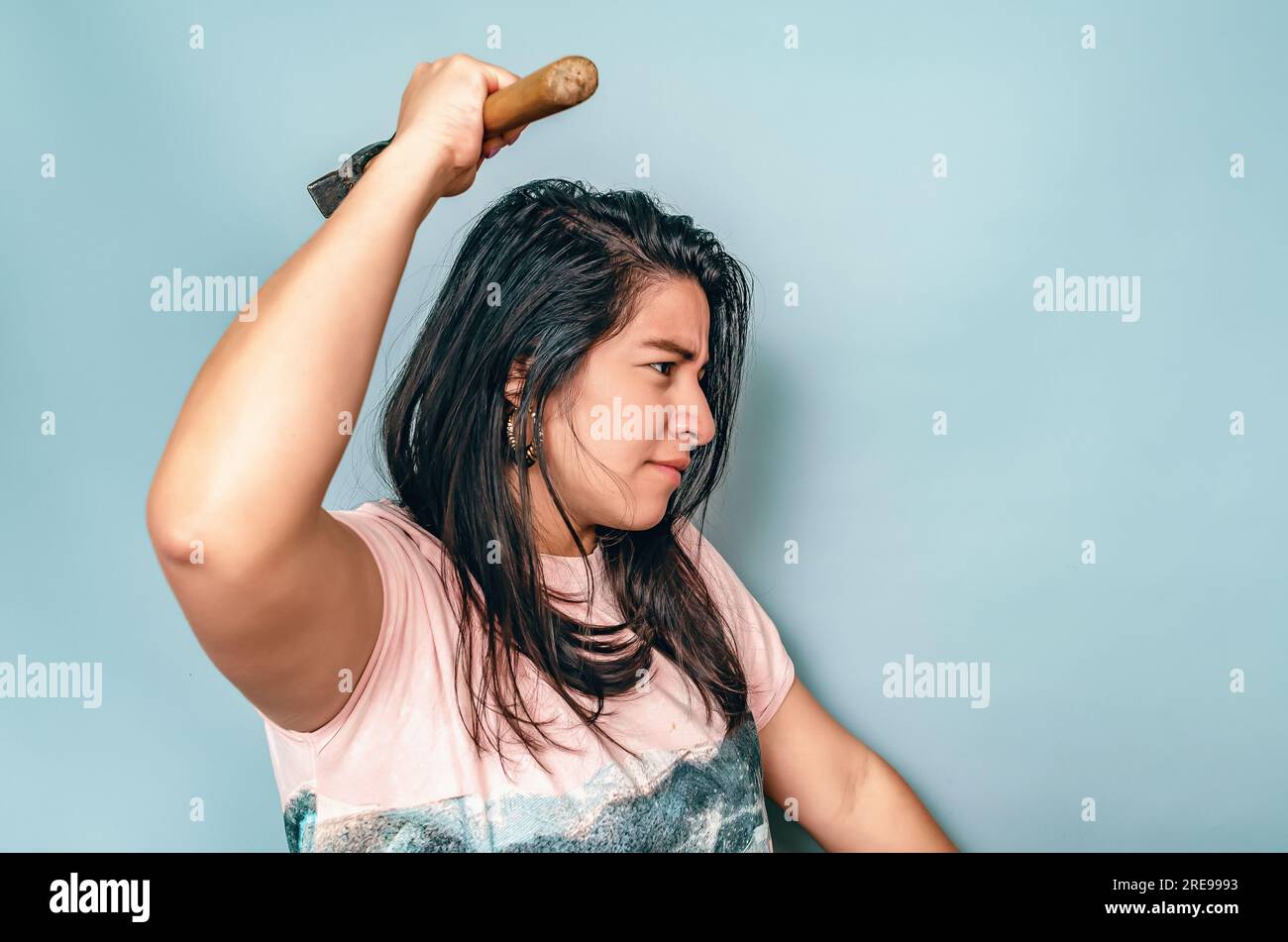 Aggressive woman with hammer. Woman in white shirt swings hammer. Side ...