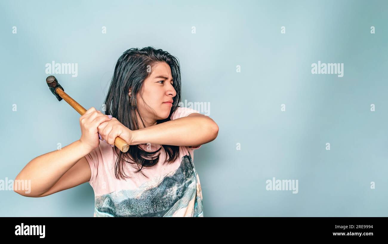 Side view woman in white shirt swings hammer. Aggressive woman with a ...