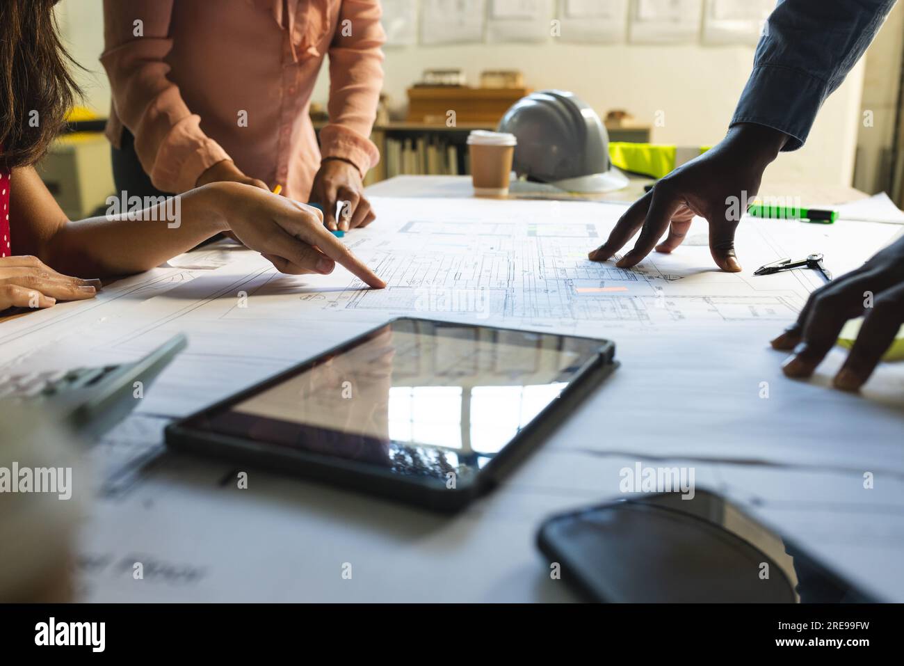 Diverse colleagues discussing work with tablet over project of building ...