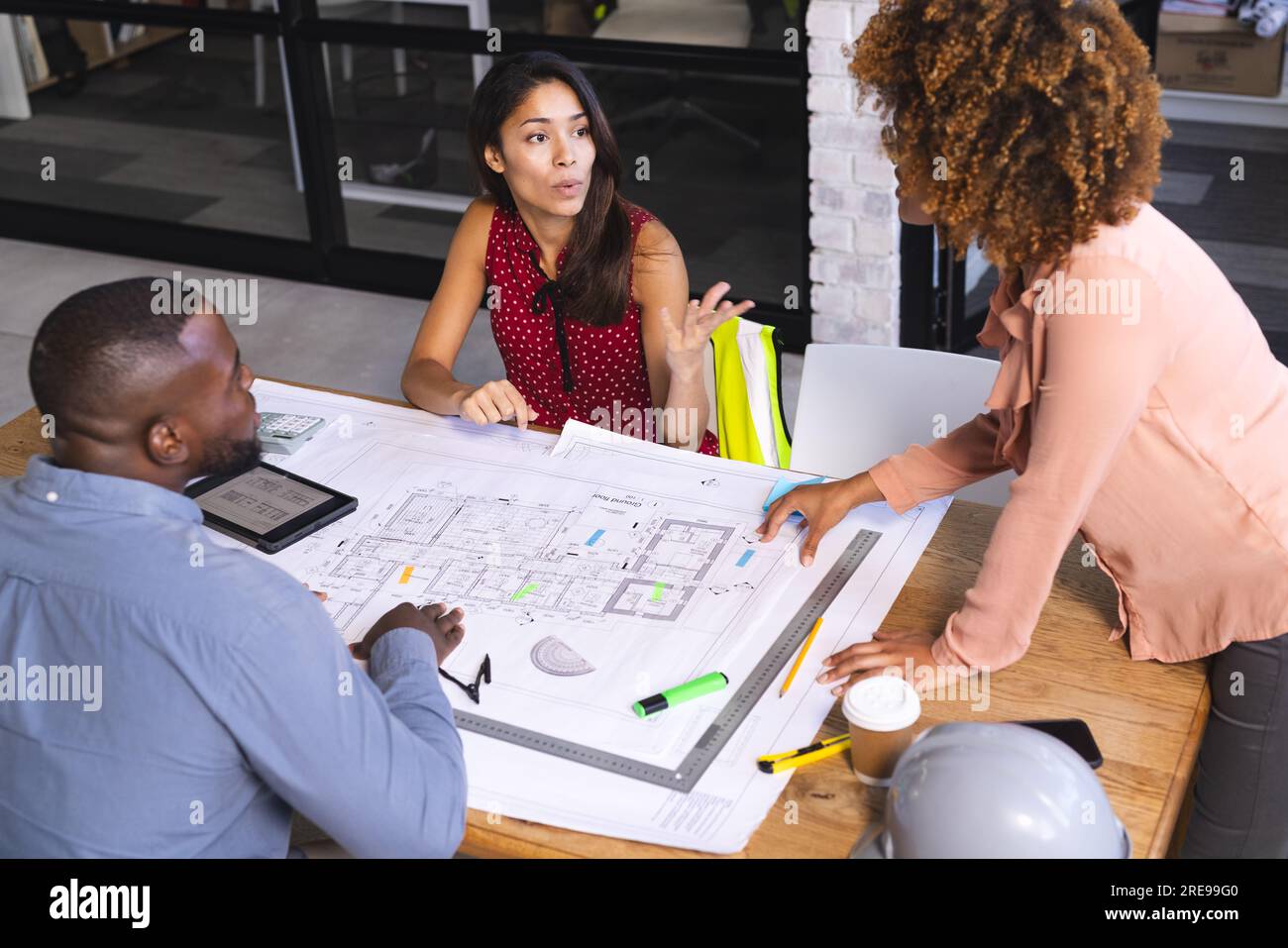 Focused diverse colleagues discussing work with tablet over project of ... Focused diverse colleagues discussing work with tablet over project of ...