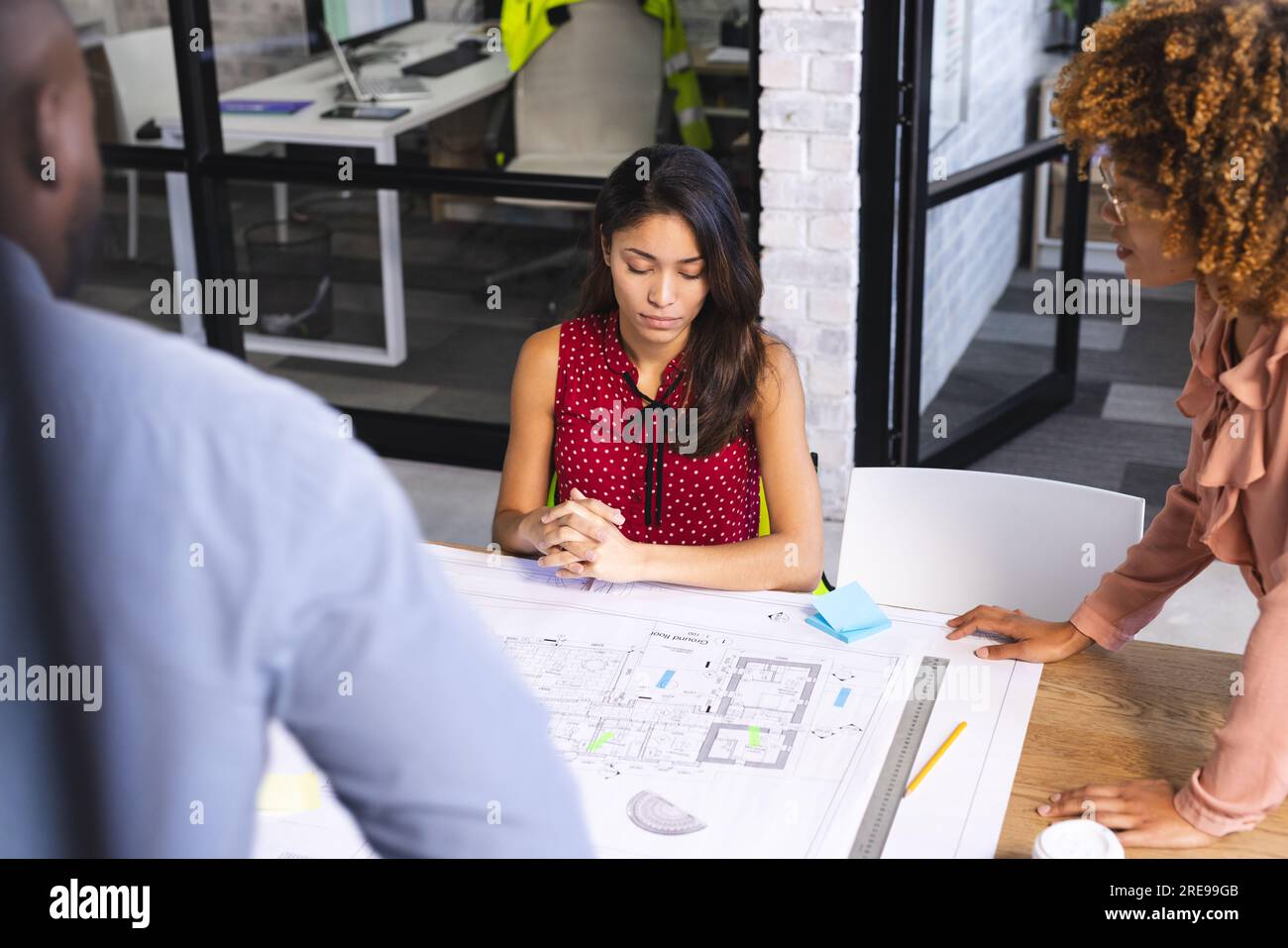 Focused diverse colleagues discussing work over project of building in ... Focused diverse colleagues discussing work over project of building in ...