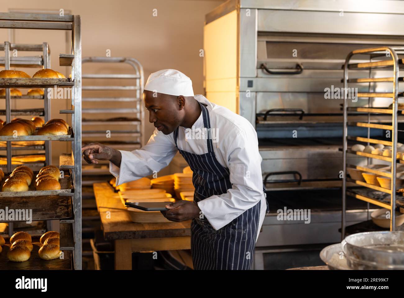 Focused african american male baker in bakery kitchen counting rolls ...
