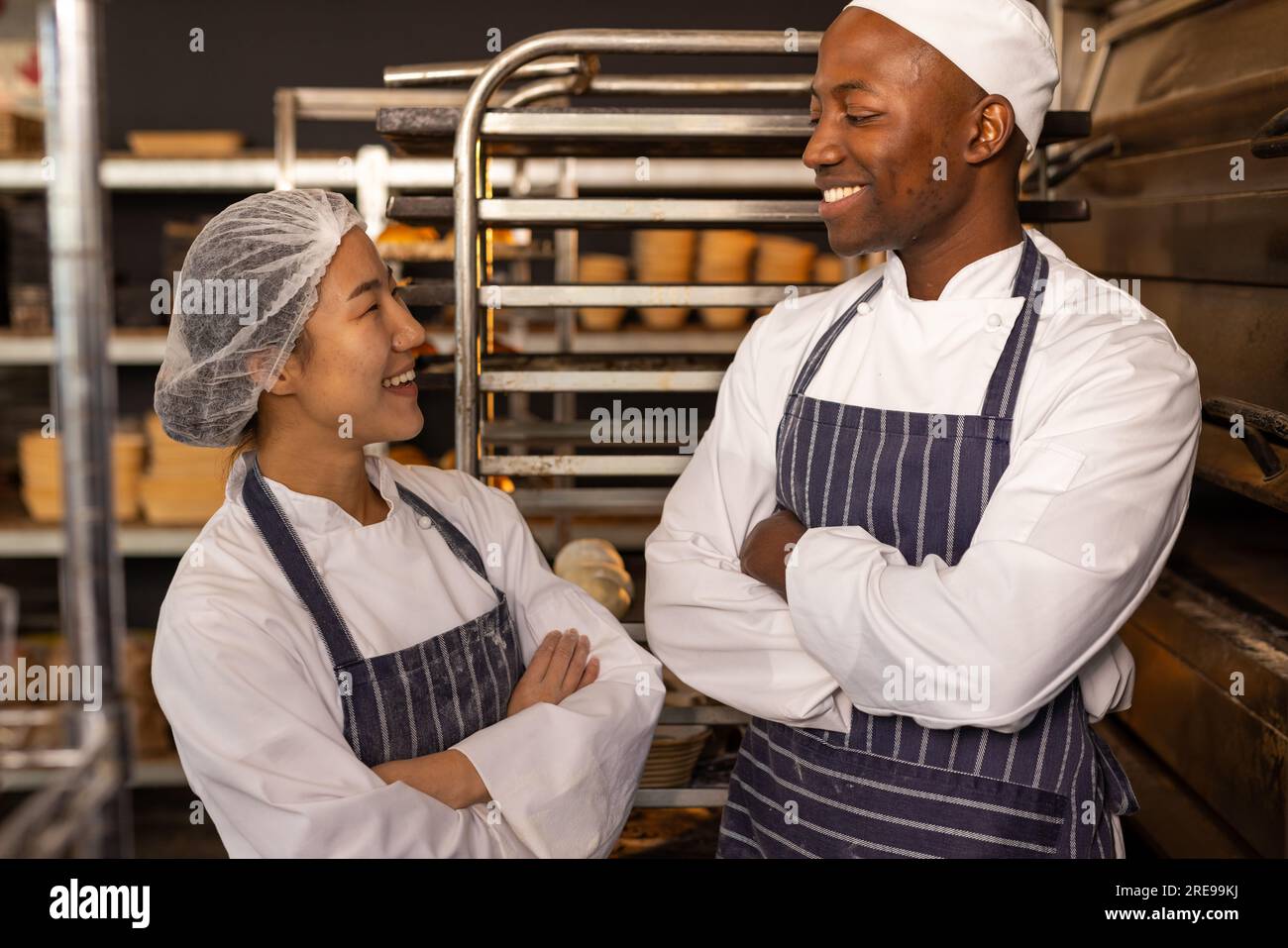 Happy diverse bakers wearing aprons in bakery with arms crossed Stock ...