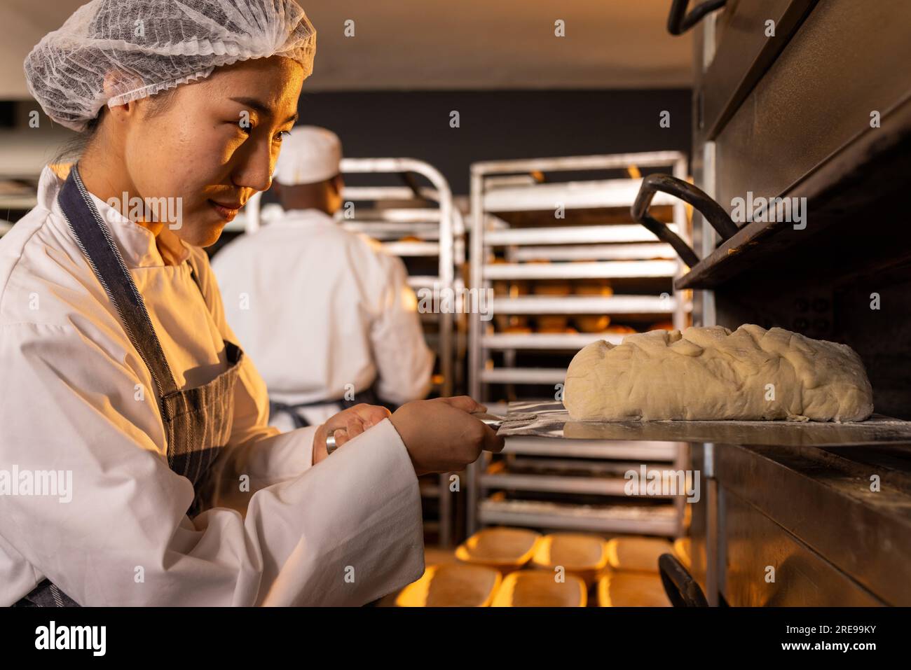 Focused diverse bakers wearing aprons in bakery kitchen and baking ...