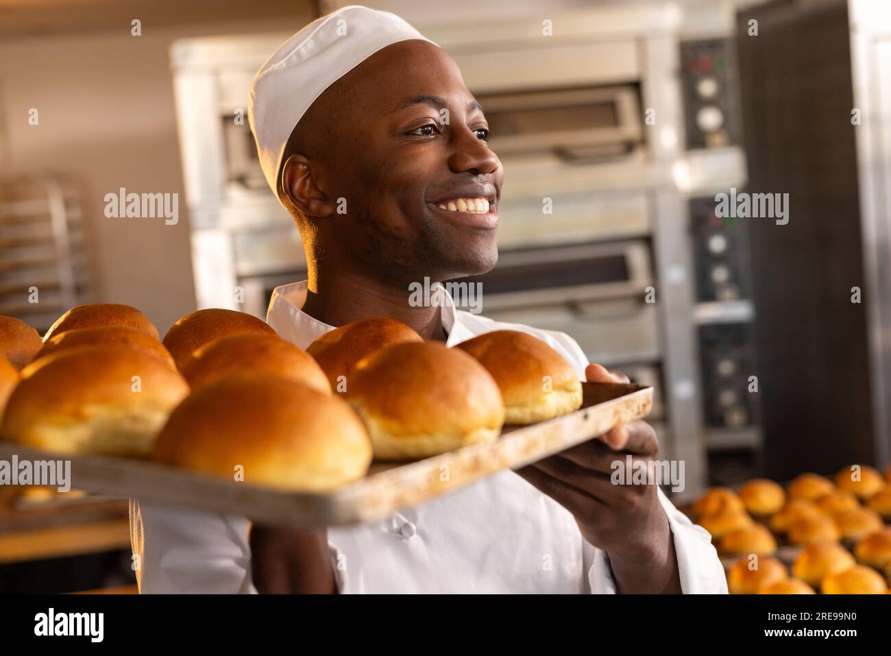 Happy african american male baker in bakery kitchen presenting fresh ...