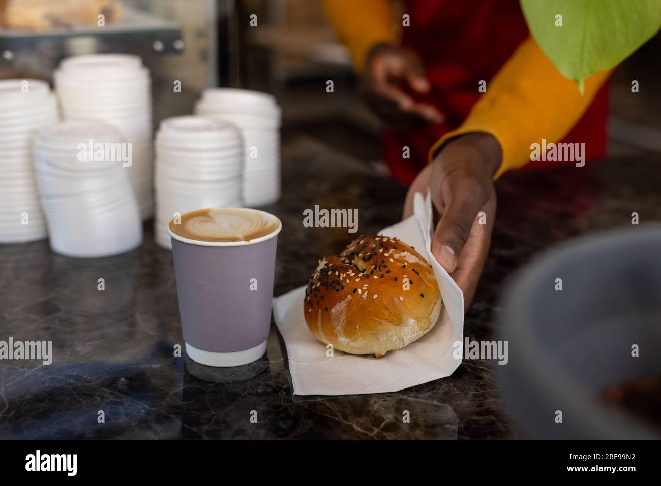 African american male bakery worker serving fresh roll and cup of ...