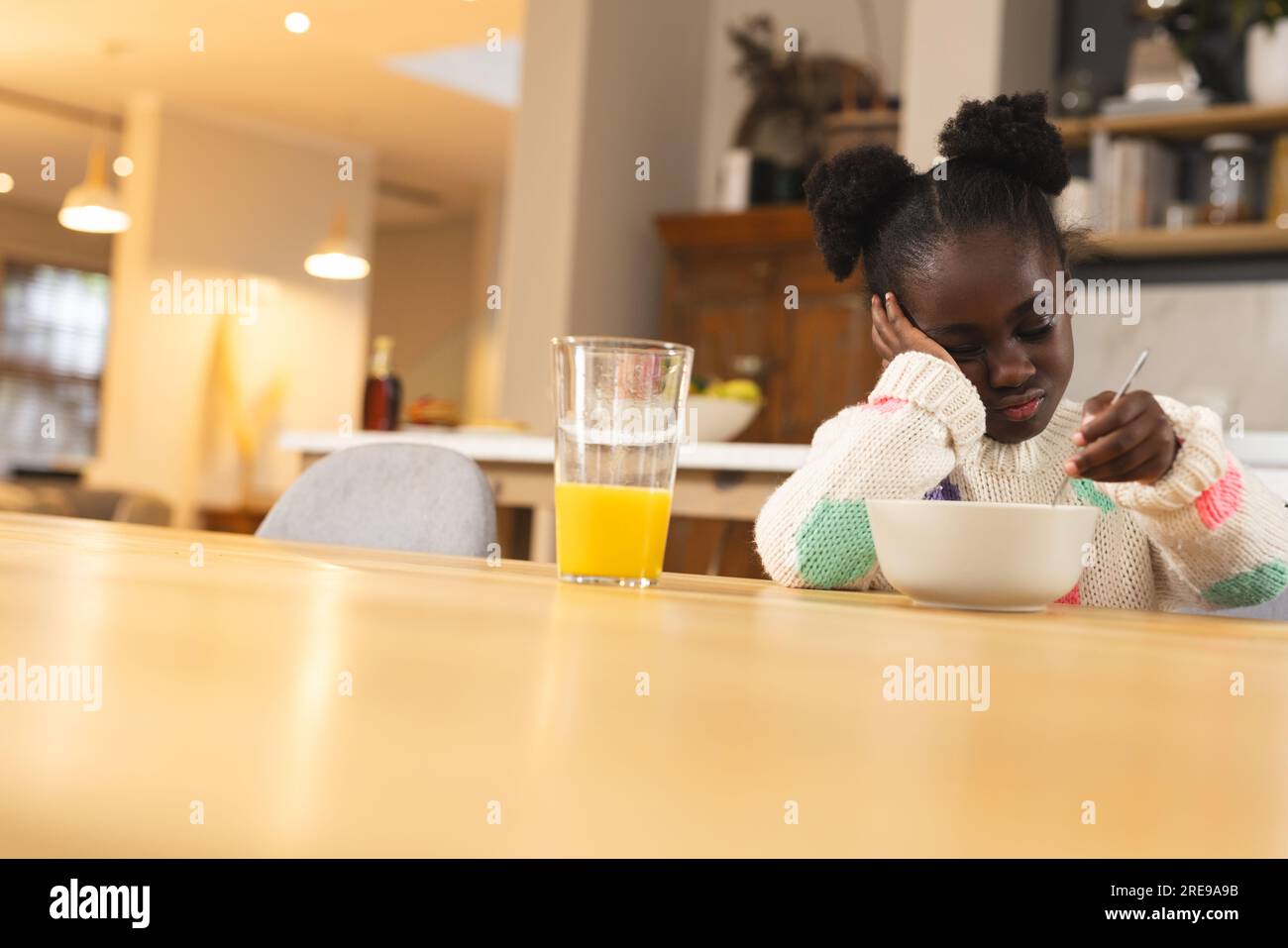 Sad african american girl sitting at table eating breakfast, copy space ...