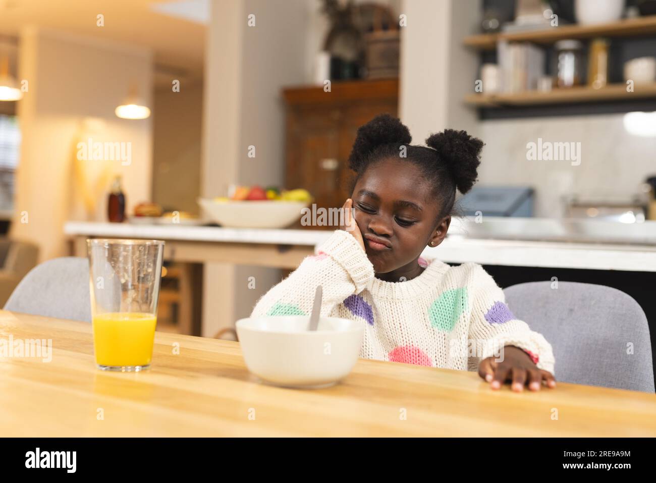 Sad african american girl sitting at table eating breakfast Stock Photo ...