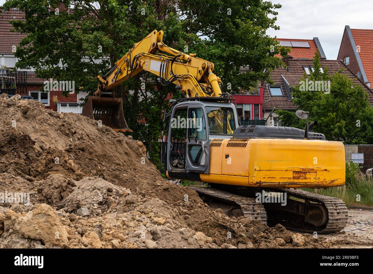Rear view of a yellow excavator piling up a pile of earth at a ...