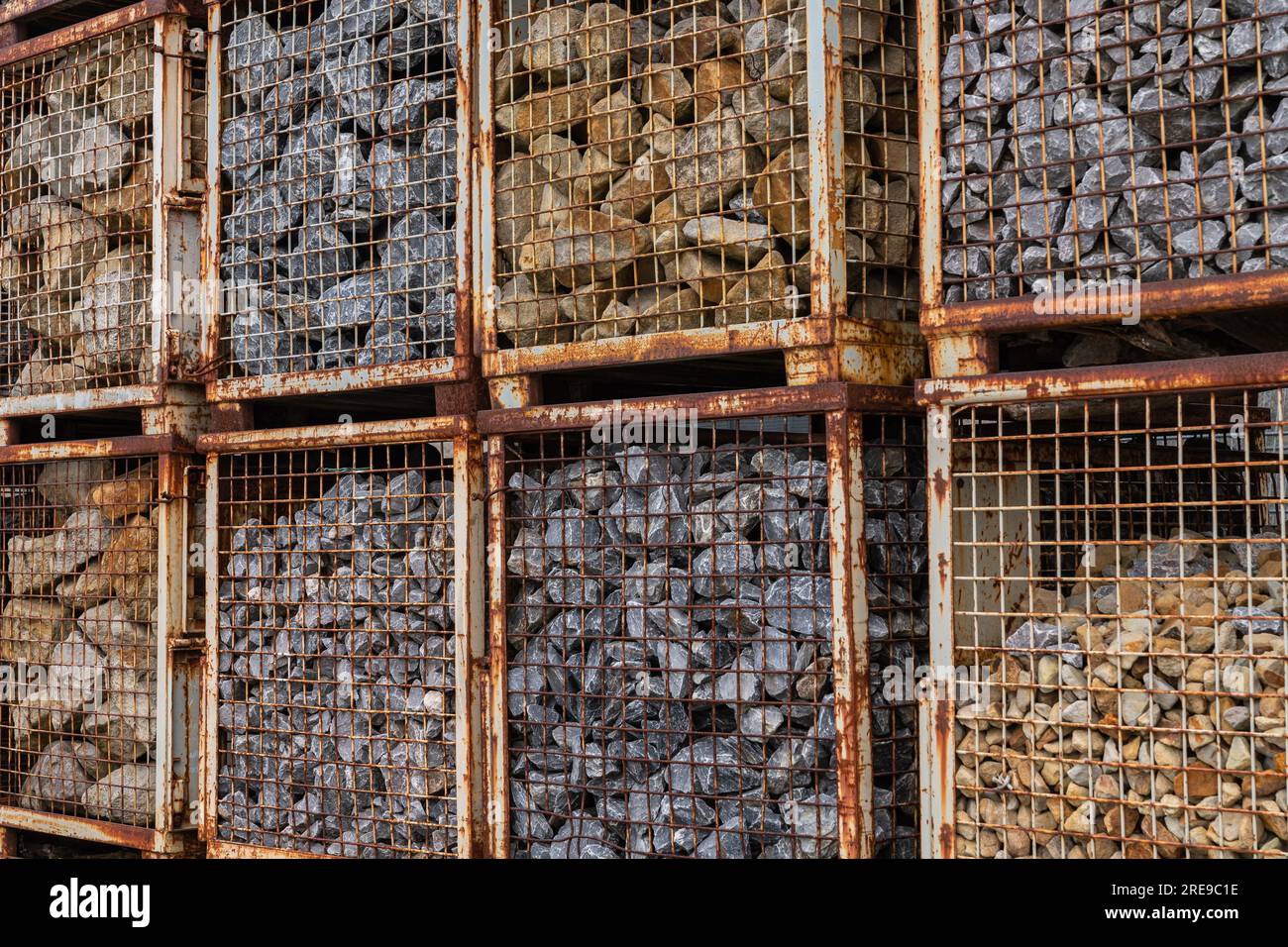Metal barred rusty containers with cobblestone and gravel of different ...