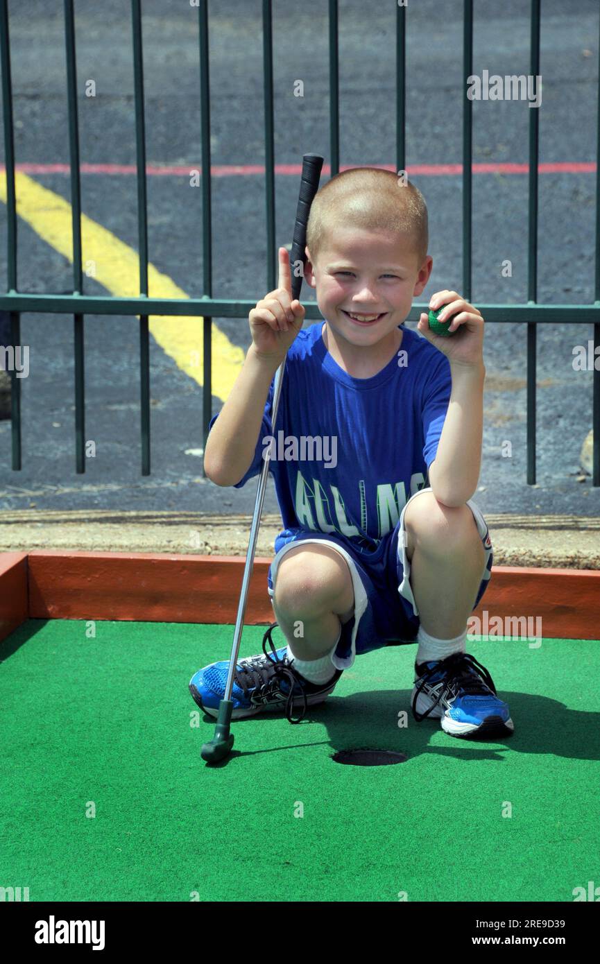 Little boy celebrates his "hole in one" by holding up one finger and ...