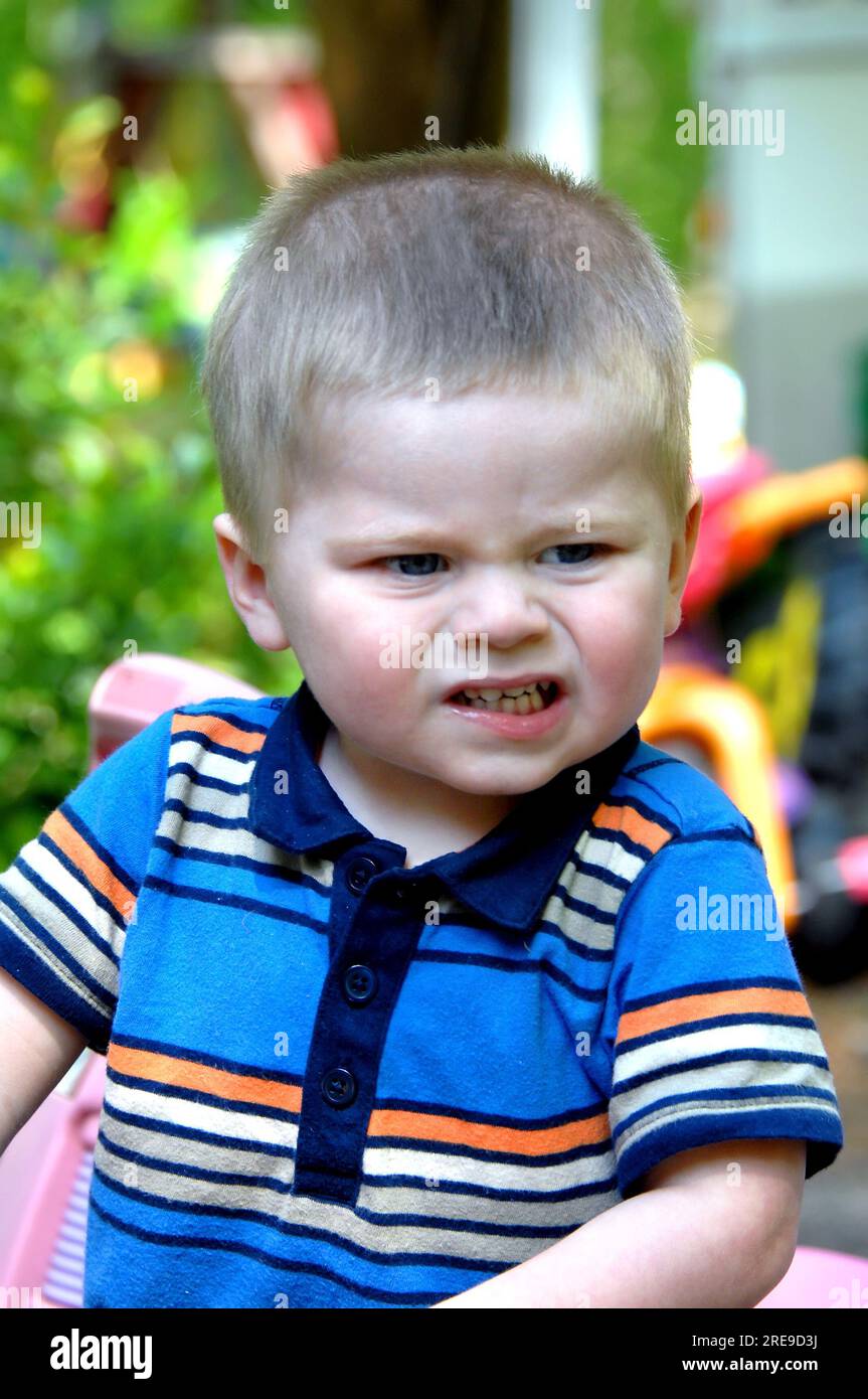 Little boy reacts with anger when siblings tease him. Image is close up ...