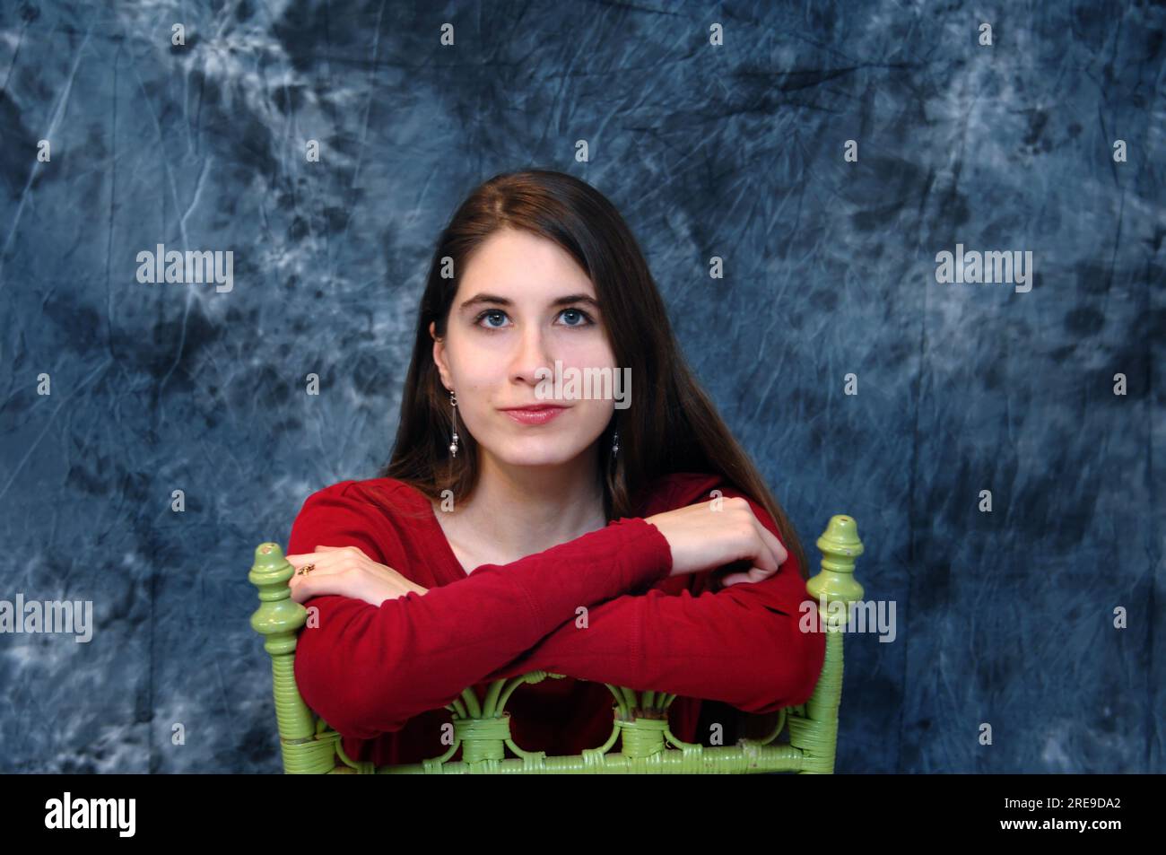 Female teen sits poised in a lime green wooden chair, turned backwards ...