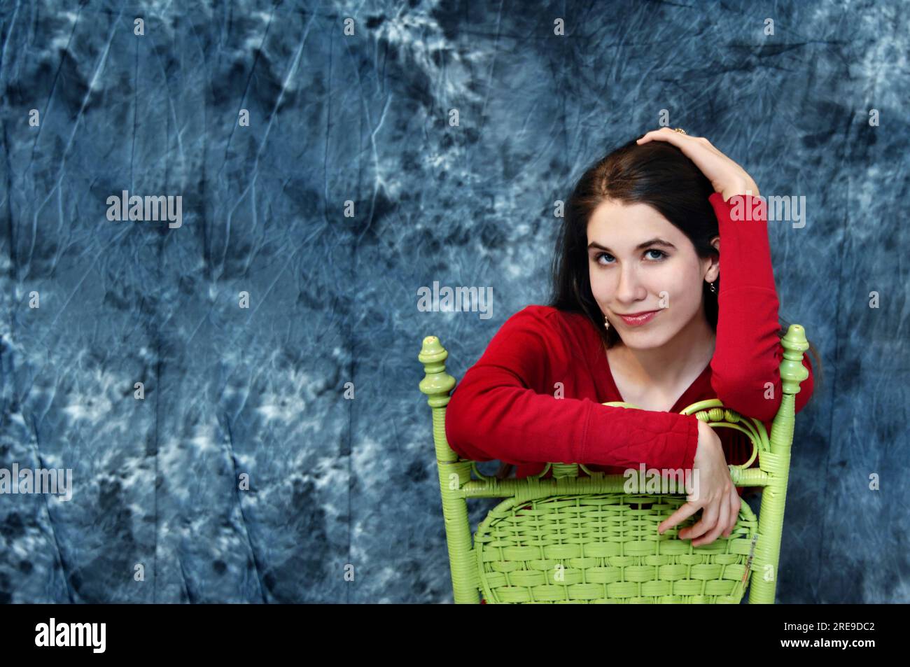 Resting On A Chair Turned Backwards This Female Teen Smiles With Her Eyes As She Leans Across